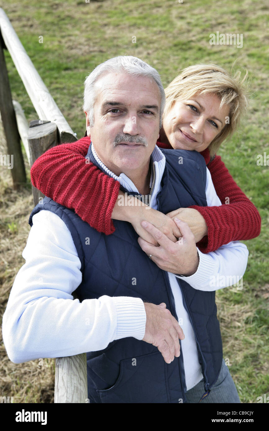 Couple leaning against fence Stock Photo - Alamy
