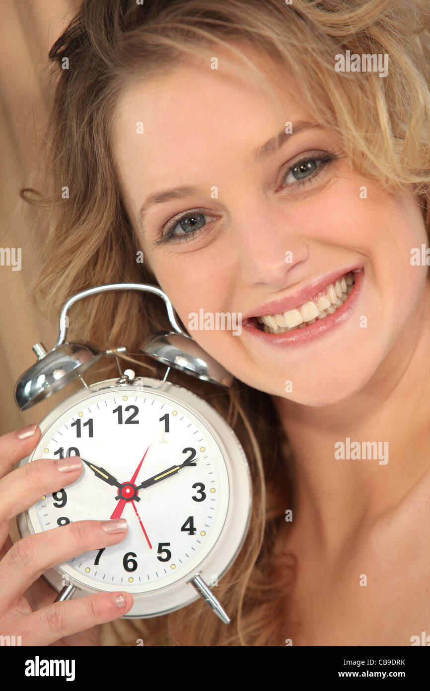 Blonde Woman holding alarm clock Stock Photo - Alamy