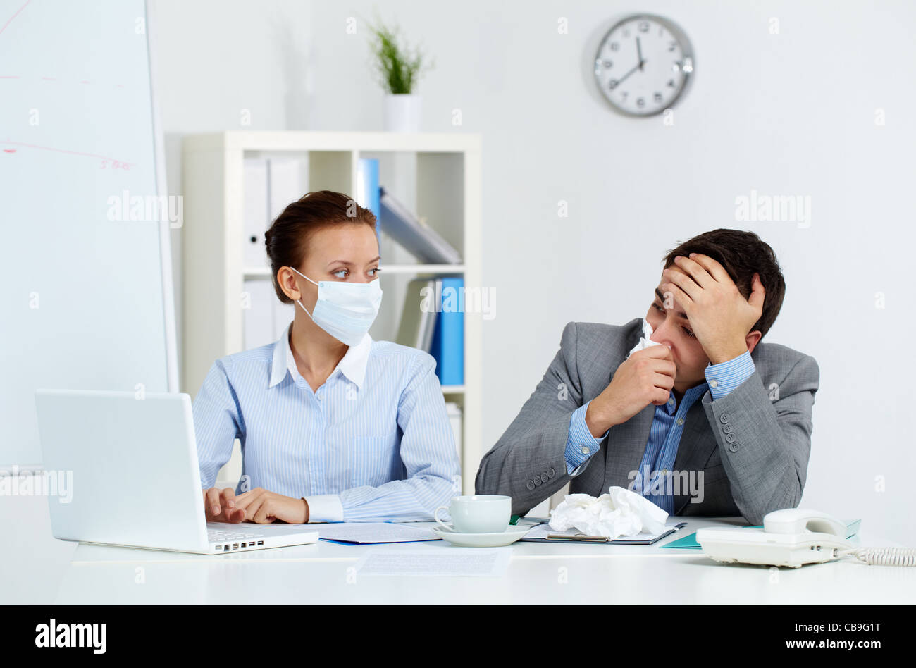 Image of sick businessman with tissue looking at laptop screen with his ...