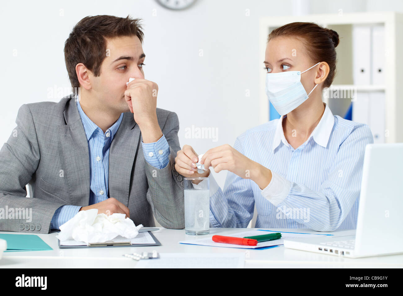 Image of sick businessman with tissue looking at his colleague in mask ...