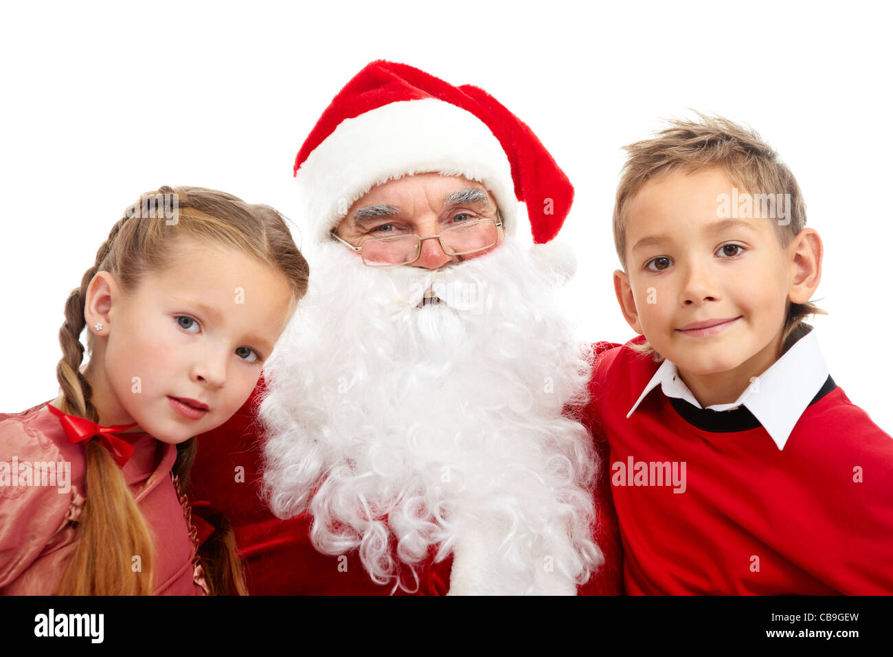 Image of happy Santa between little boy and girl looking at camera ...