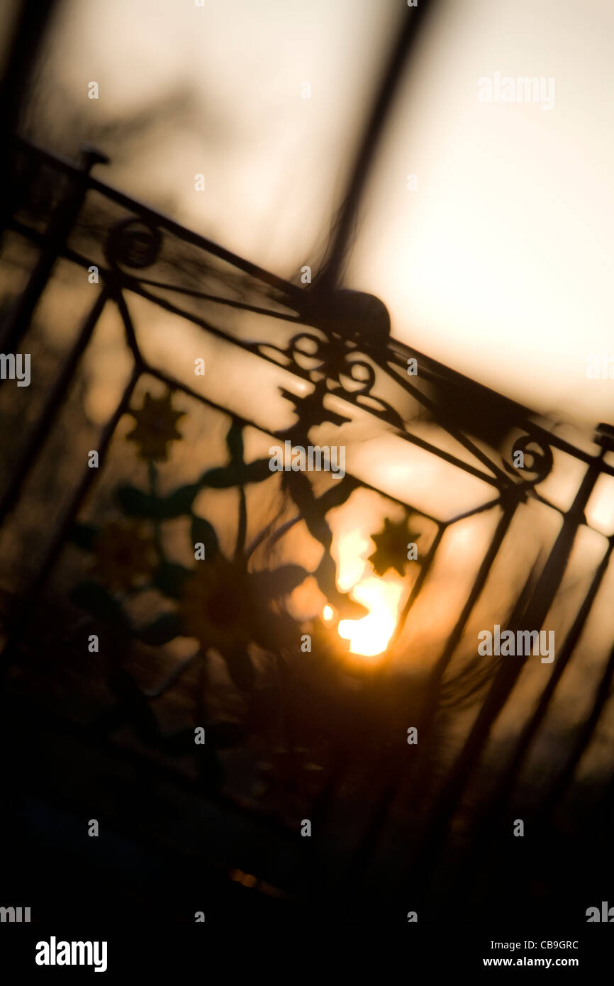 Blurred image of setting sun through circle on metal fence in park ...