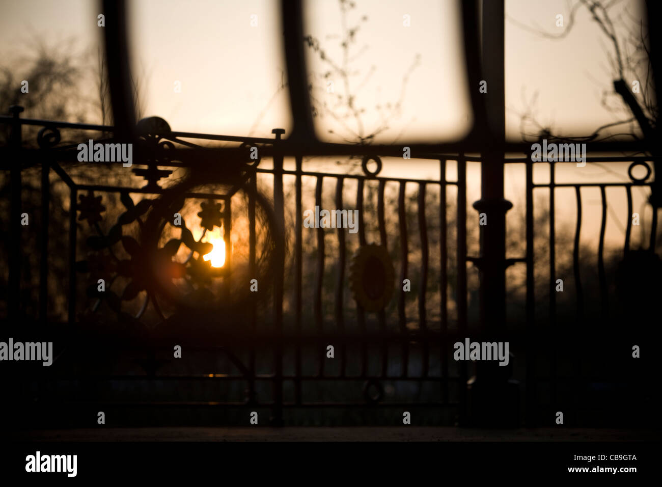 An image of setting sun through circle on metal fence in park Stock ...