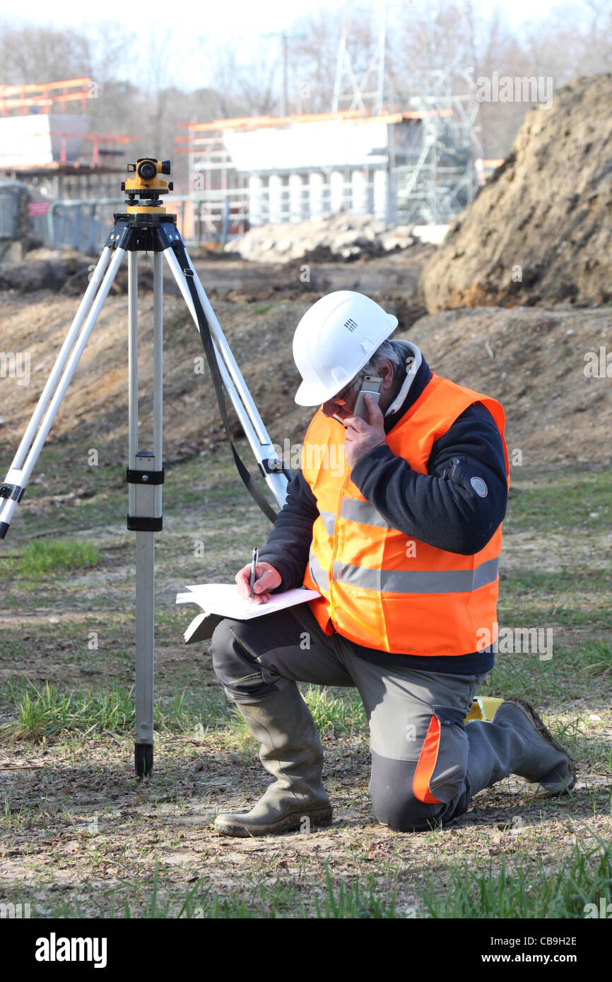 A land surveyor writing in his notebook while talking on the phone ...