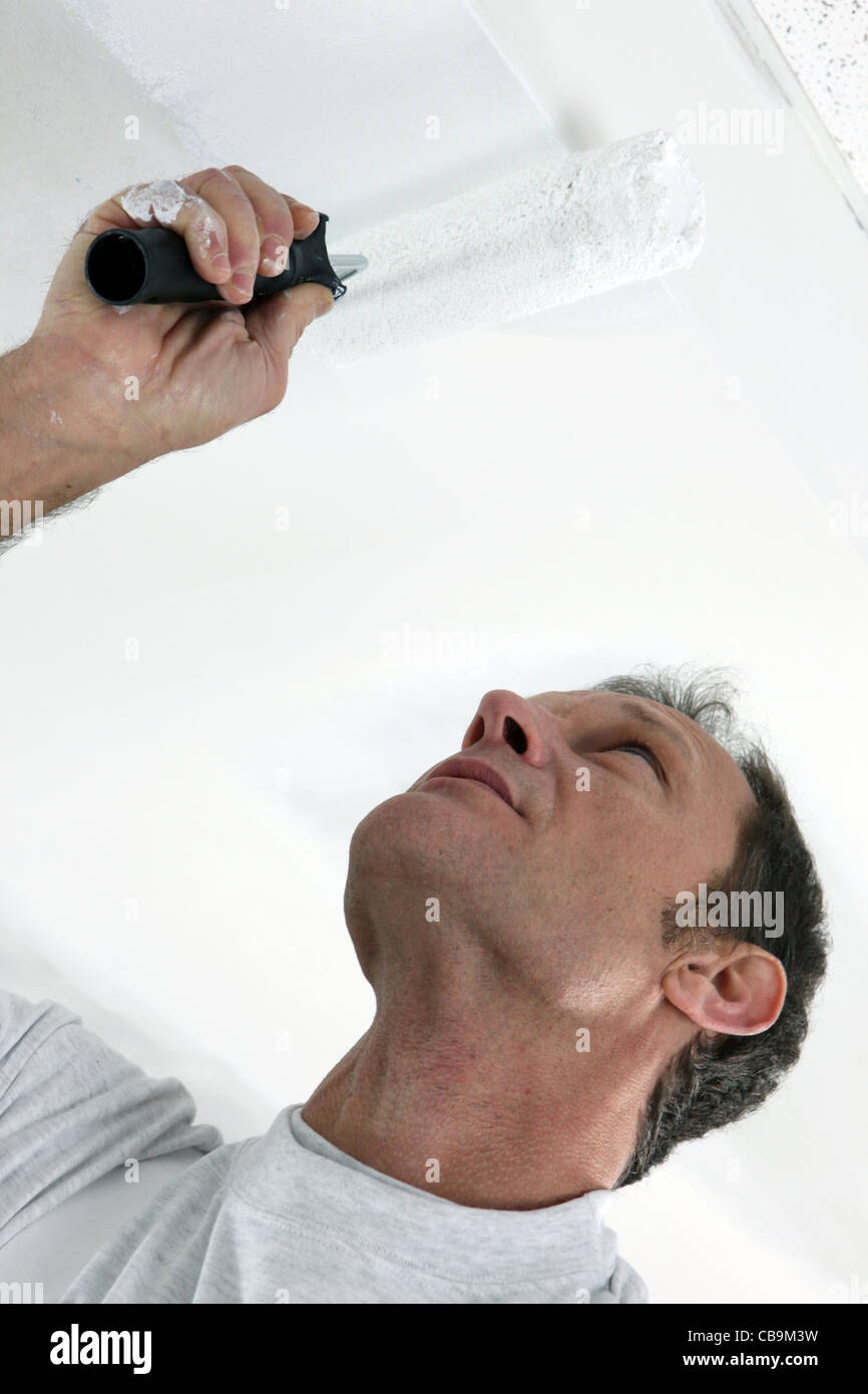 Man painting ceiling with roller Stock Photo - Alamy