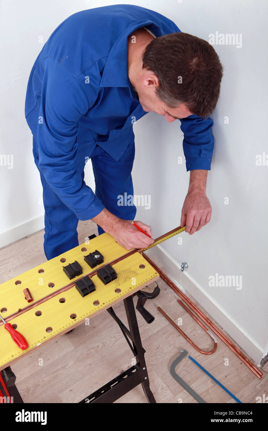 Laborer measuring copper pipe Stock Photo - Alamy
