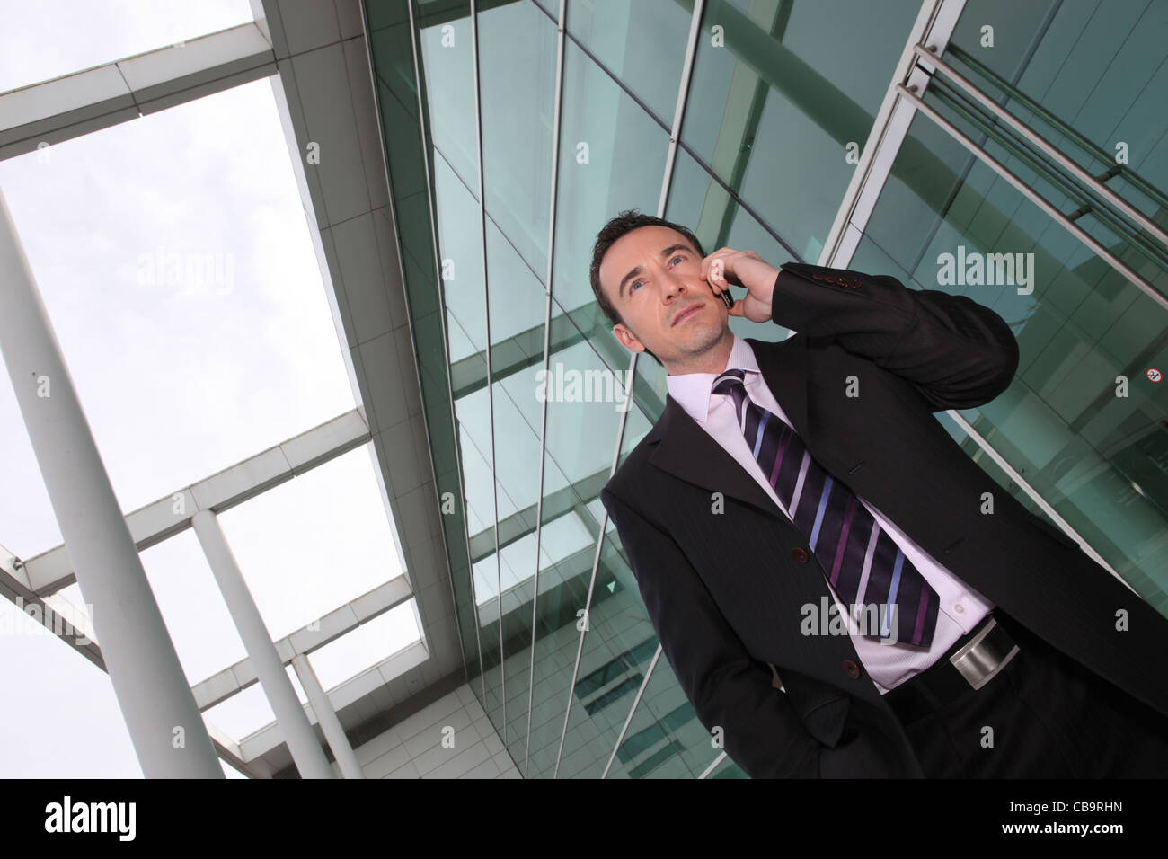 Man using a mobile outside a glass fronted building Stock Photo - Alamy