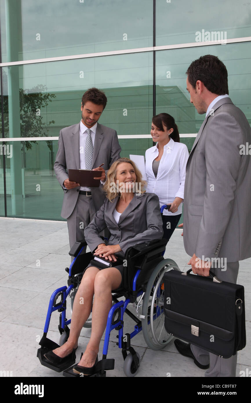 Businesswoman in a wheelchair with colleagues outside an office ...