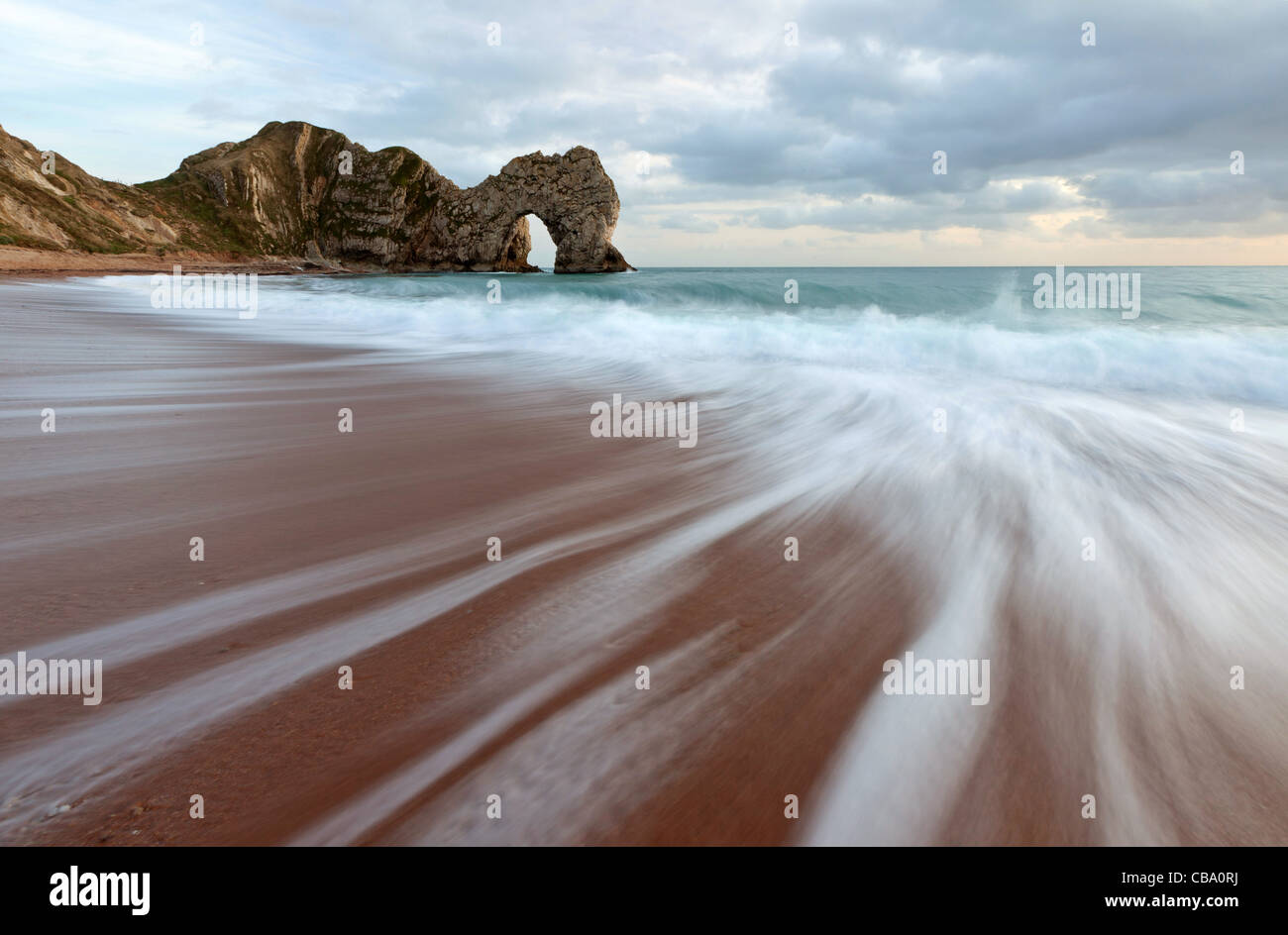 Dramatic water movement with Durdle Door to left Stock Photo - Alamy