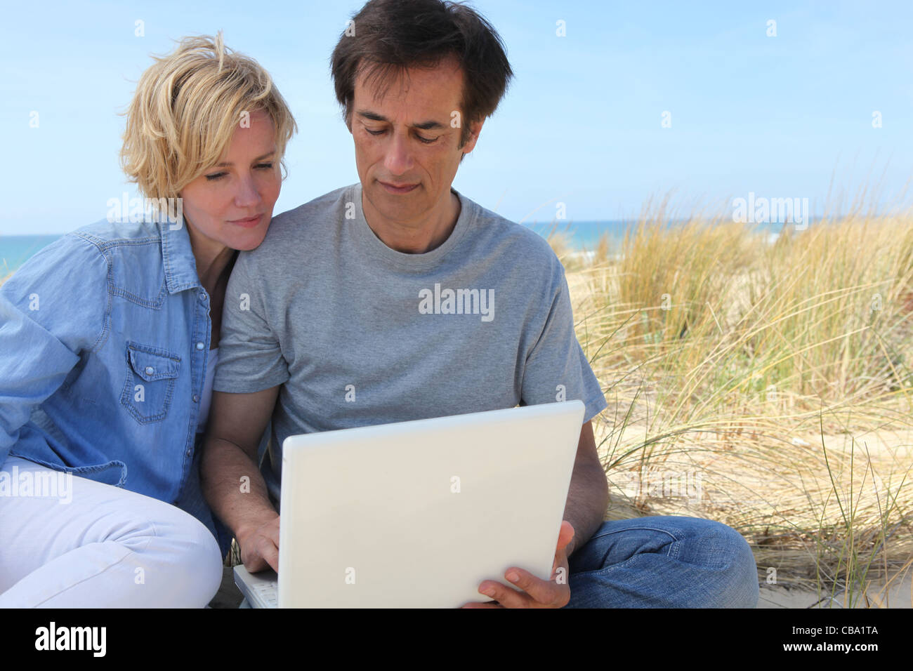 Couple on laptop at the beach Stock Photo - Alamy