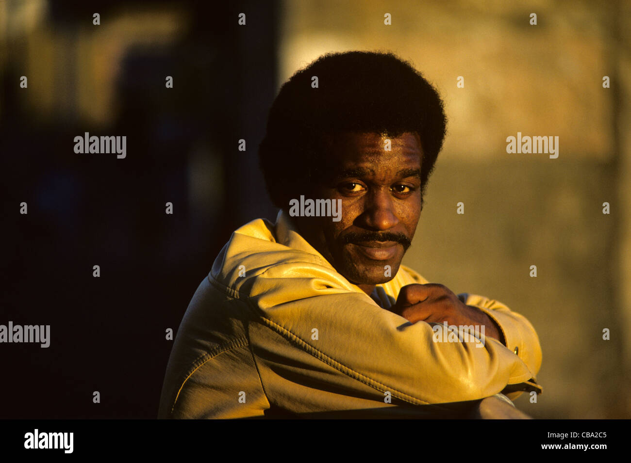 Black man street portrait leaning on railing looking into camera ...