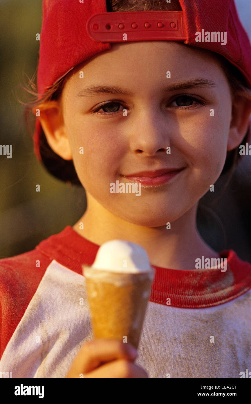 Little League Baseball player eating ice cream after game sunset light ...