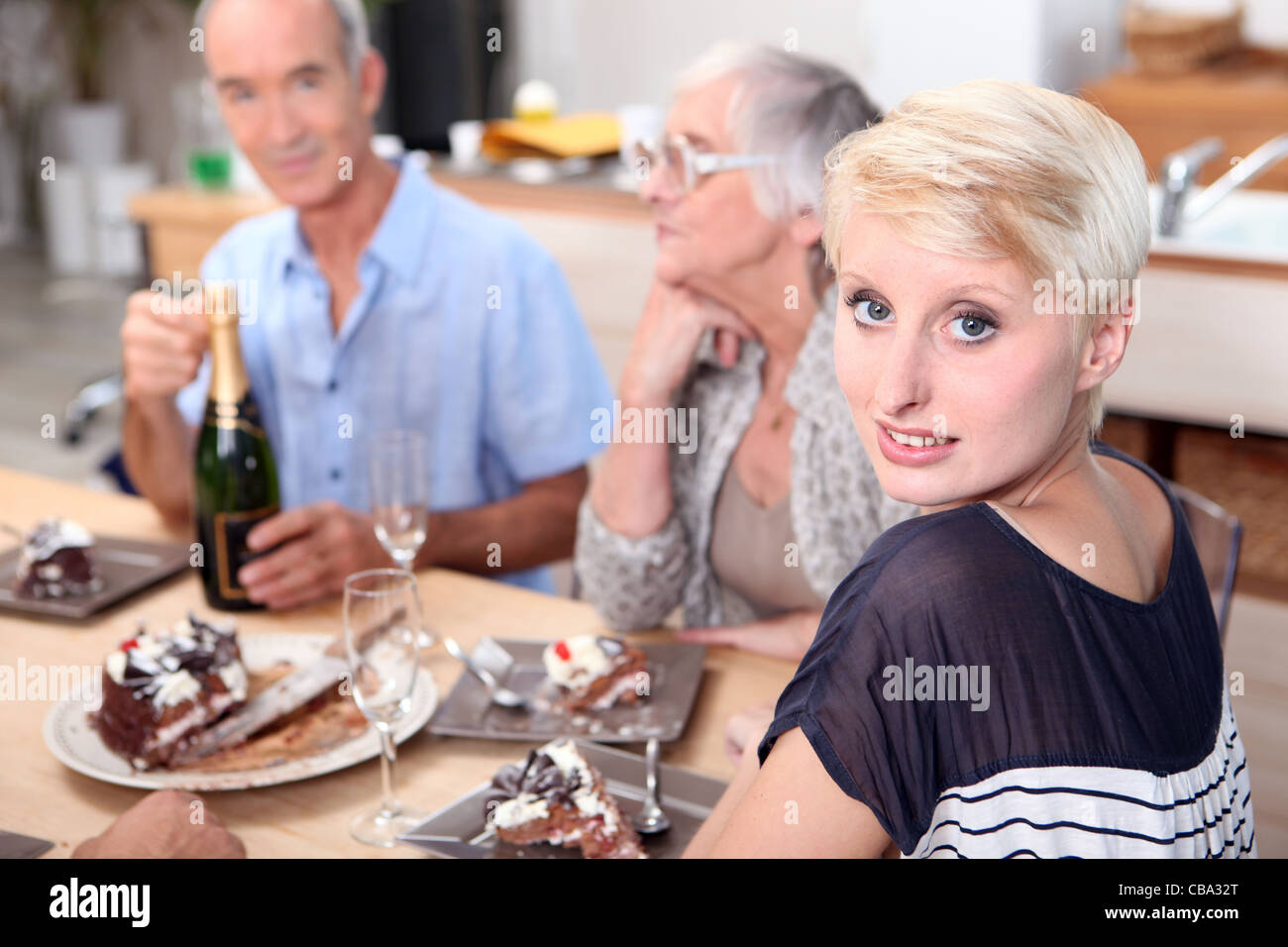 Family gathered around table eating cake Stock Photo - Alamy