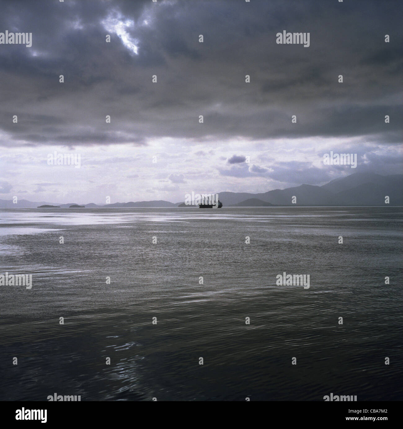 Cargo ship out at sea, near land Stock Photo - Alamy