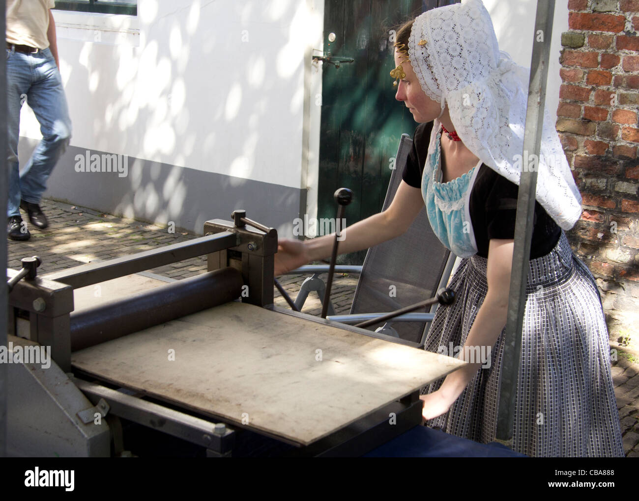 Woman in historical costume producing prints on a traditional press in ...