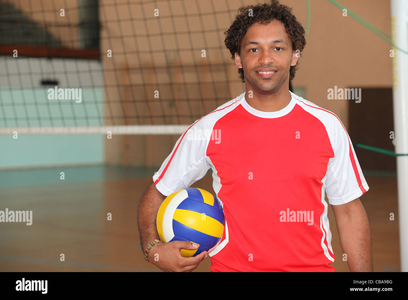 Volleyball player stood with ball under arm Stock Photo - Alamy