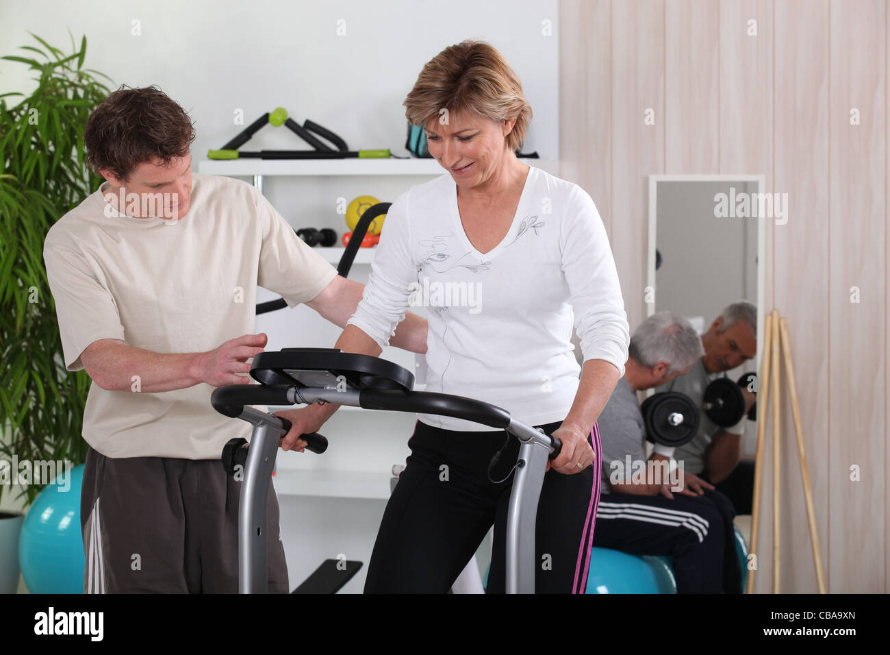 blonde middle-aged woman on treadmill coached by physiotherapist Stock ...