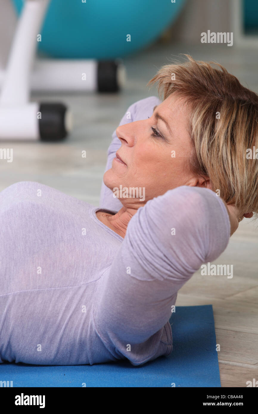 Woman doing sit-ups on gym mat Stock Photo - Alamy