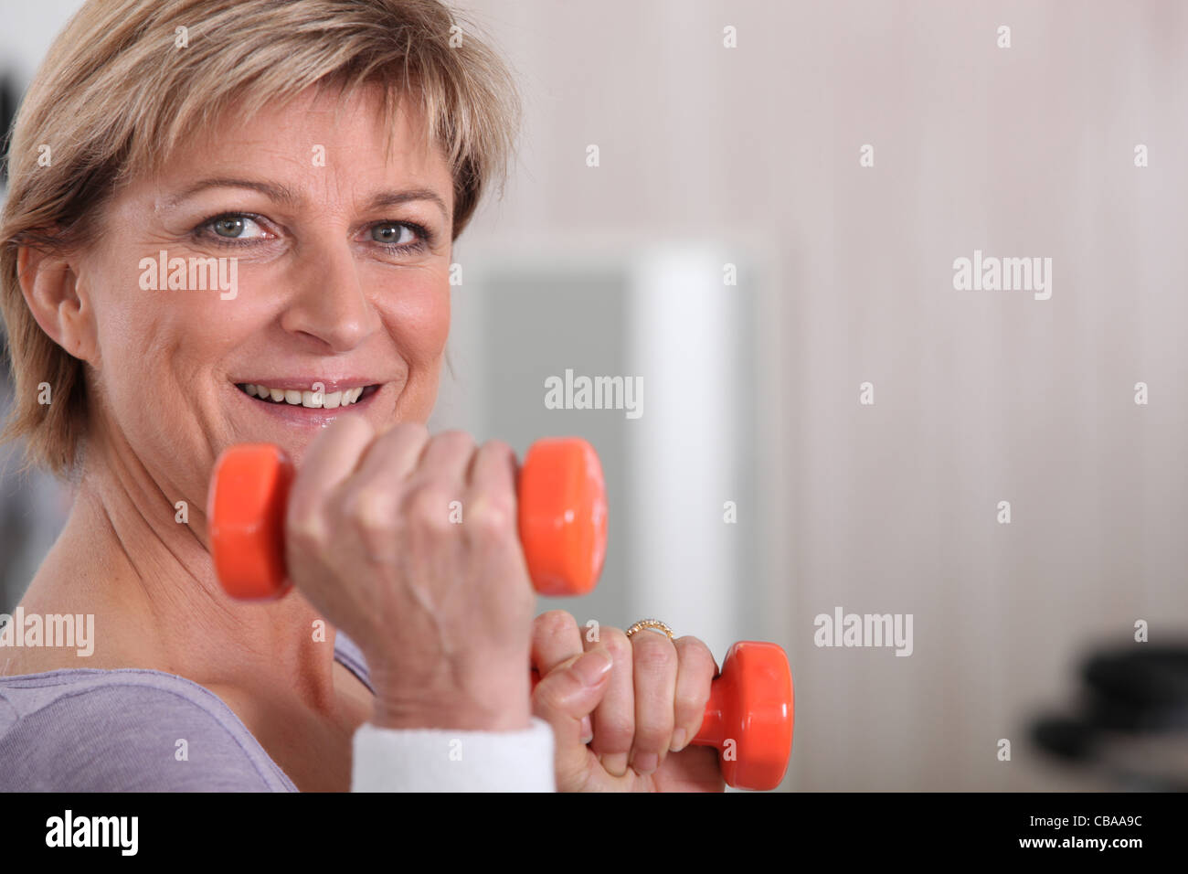 Mature woman using dumbbells Stock Photo - Alamy