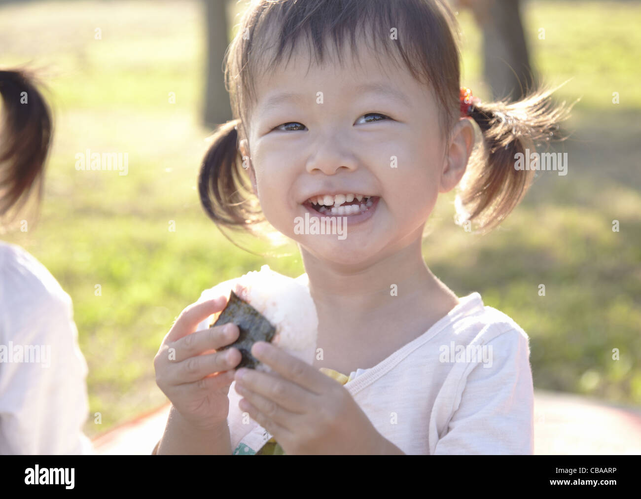 Girl eating rice ball in a park Stock Photo - Alamy
