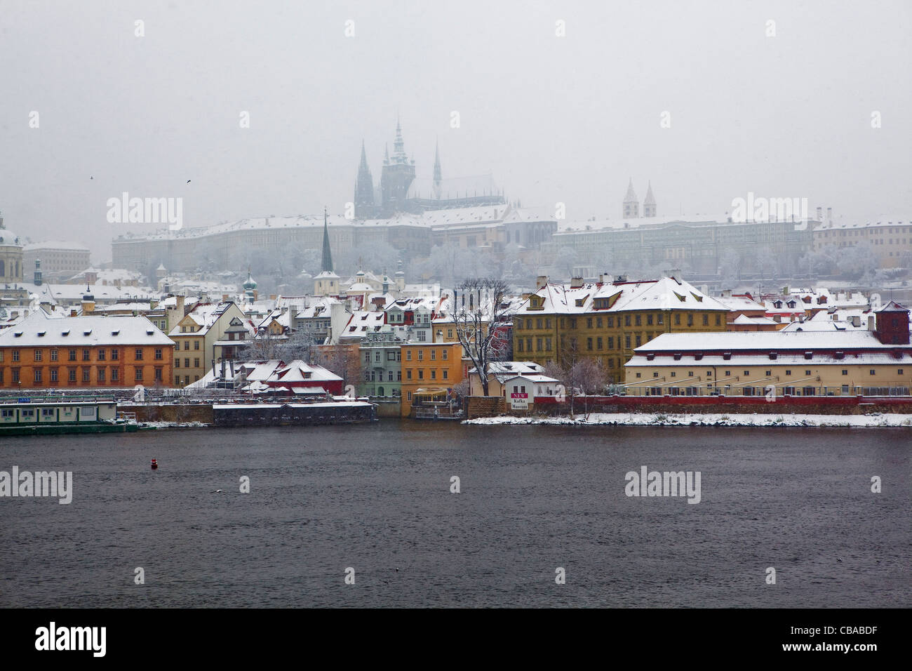 Prague castle covert in mist and snow covered roofs of Mala Strana seen ...