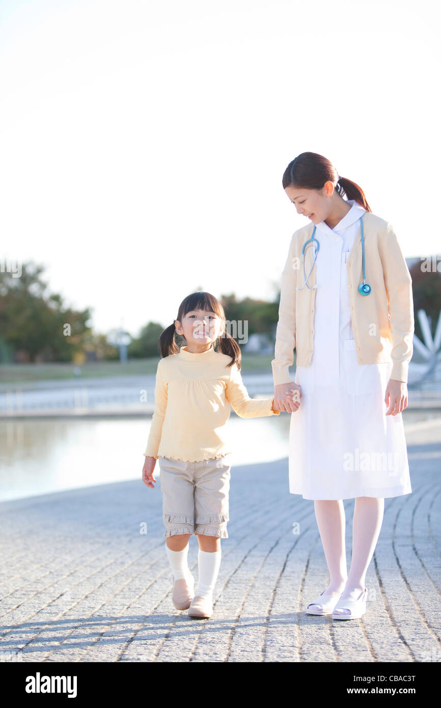 Young Female Nurse and Girl Walking Hand in Hand Stock Photo - Alamy