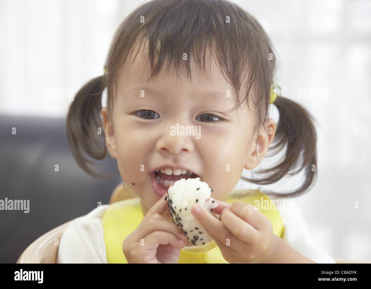 Girl eating rice ball with a smile Stock Photo - Alamy