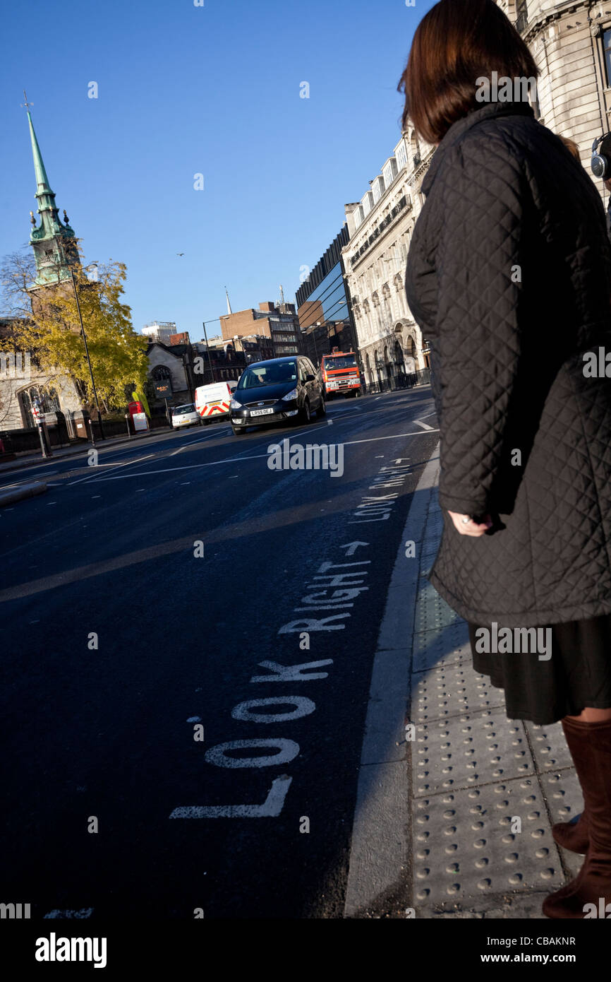 A pedestrian waiting to cross the road at a pedestrian crossing, London ...