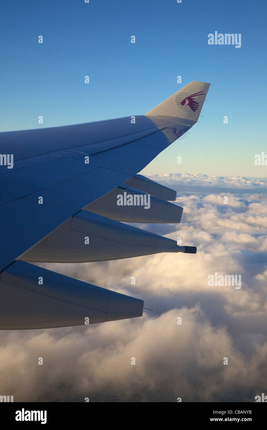 View through passenger jet window of Qatar airliner wing, clouds and ...