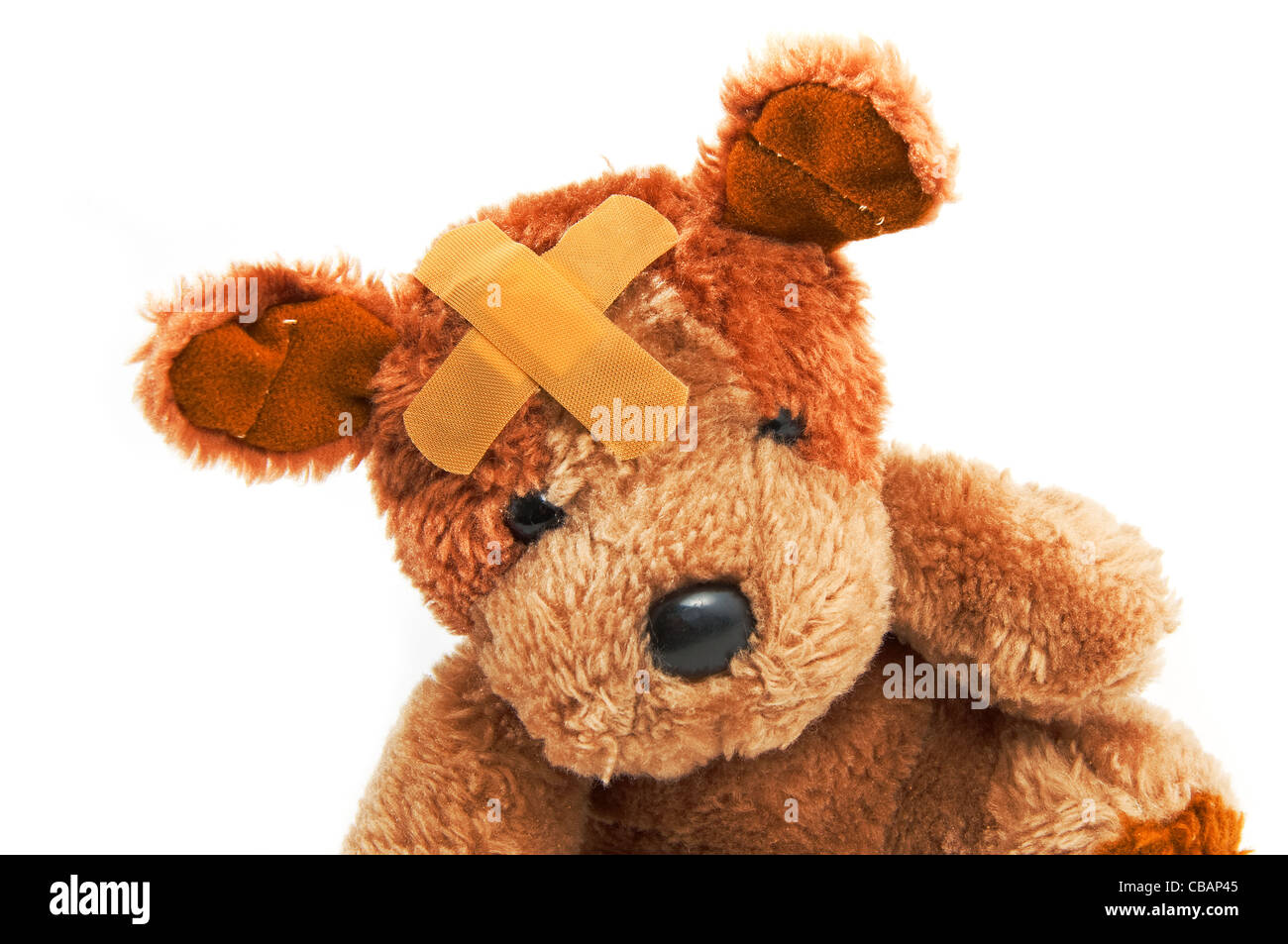 Cute little teddy bear with plaster on his head over a white background ...