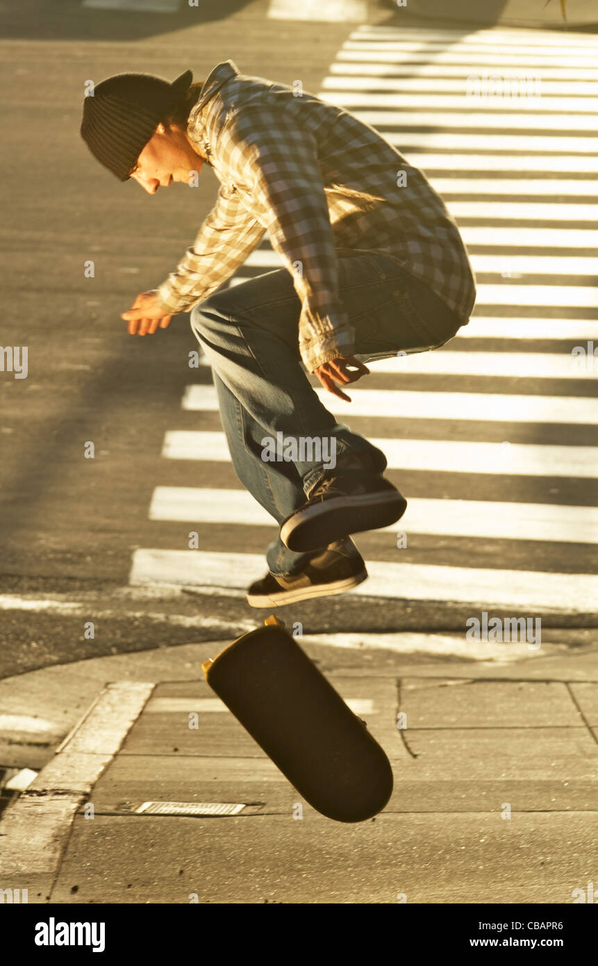 A male skateboarder doing an ollie jump trick on a sidewalk Stock Photo ...