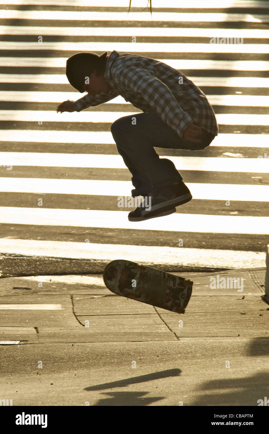 A male skateboarder doing an ollie jump trick on a sidewalk Stock Photo ...