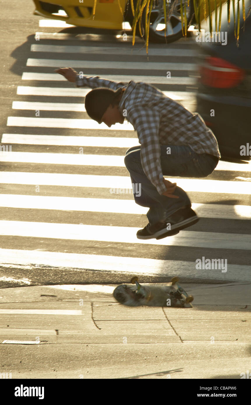 A male skateboarder doing an ollie jump trick on a sidewalk Stock Photo ...