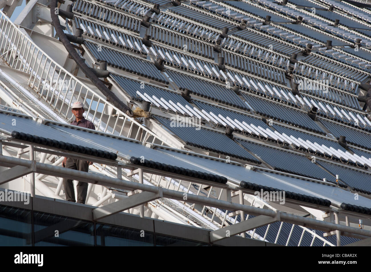 A worker on the roof of the Micro-E Hotel, world's largest solar ...
