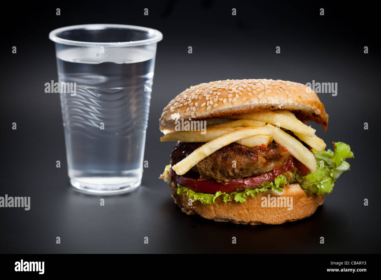 Hamburger with glass of water on black background Stock Photo - Alamy