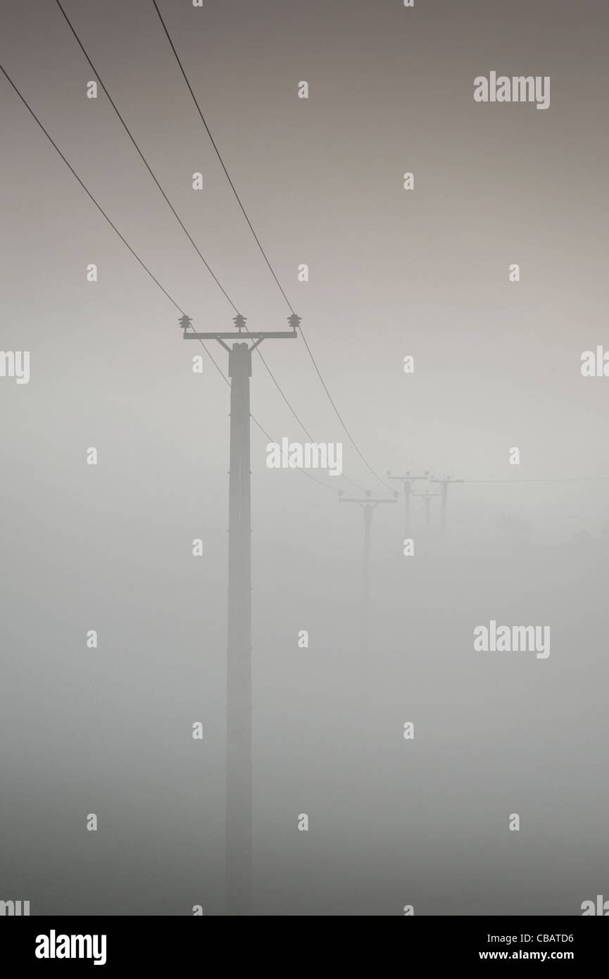 Power lines stretch across the hillside on a foggy cold morning in ...