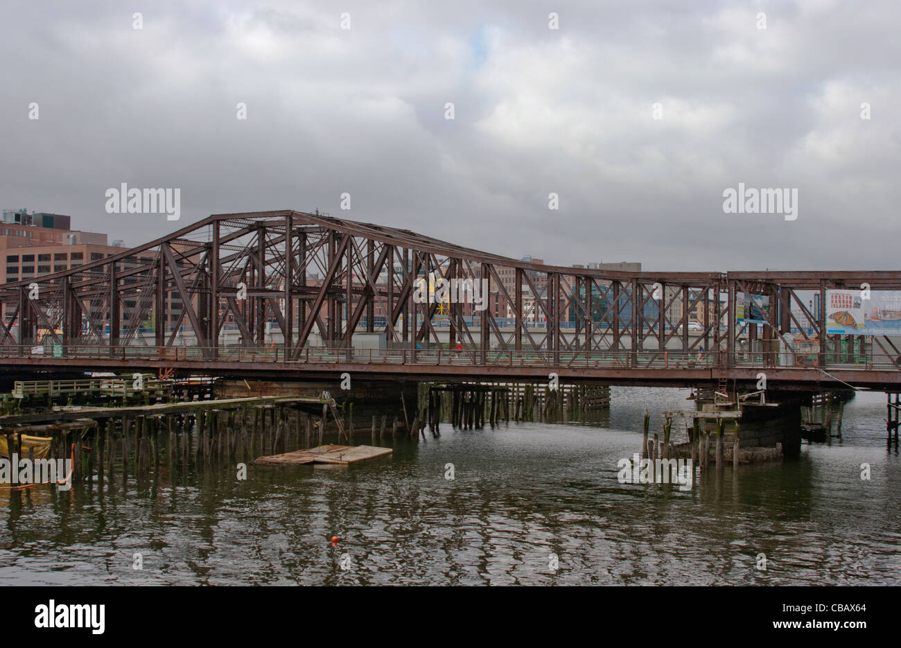 rusty old footbridge over Boston harbor with wood pilings and buildings ...