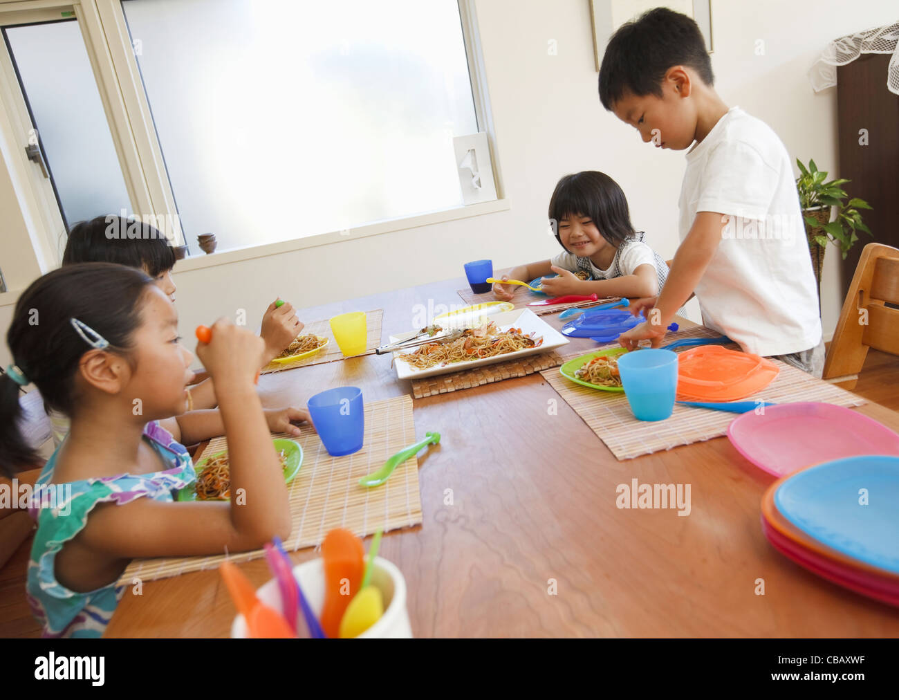 Children eating meal at dining table Stock Photo - Alamy