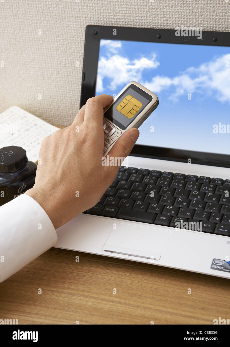 Hand holding mobile phone with IC chip and laptop Stock Photo - Alamy