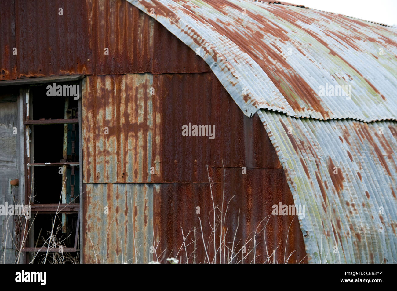 Rusty corrugated metal semi circular building with broken window and ...