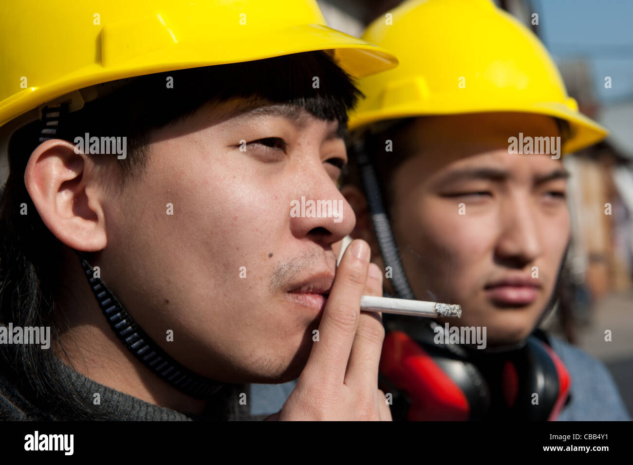 Construction workers standing and smoking on a street in an industrial ...