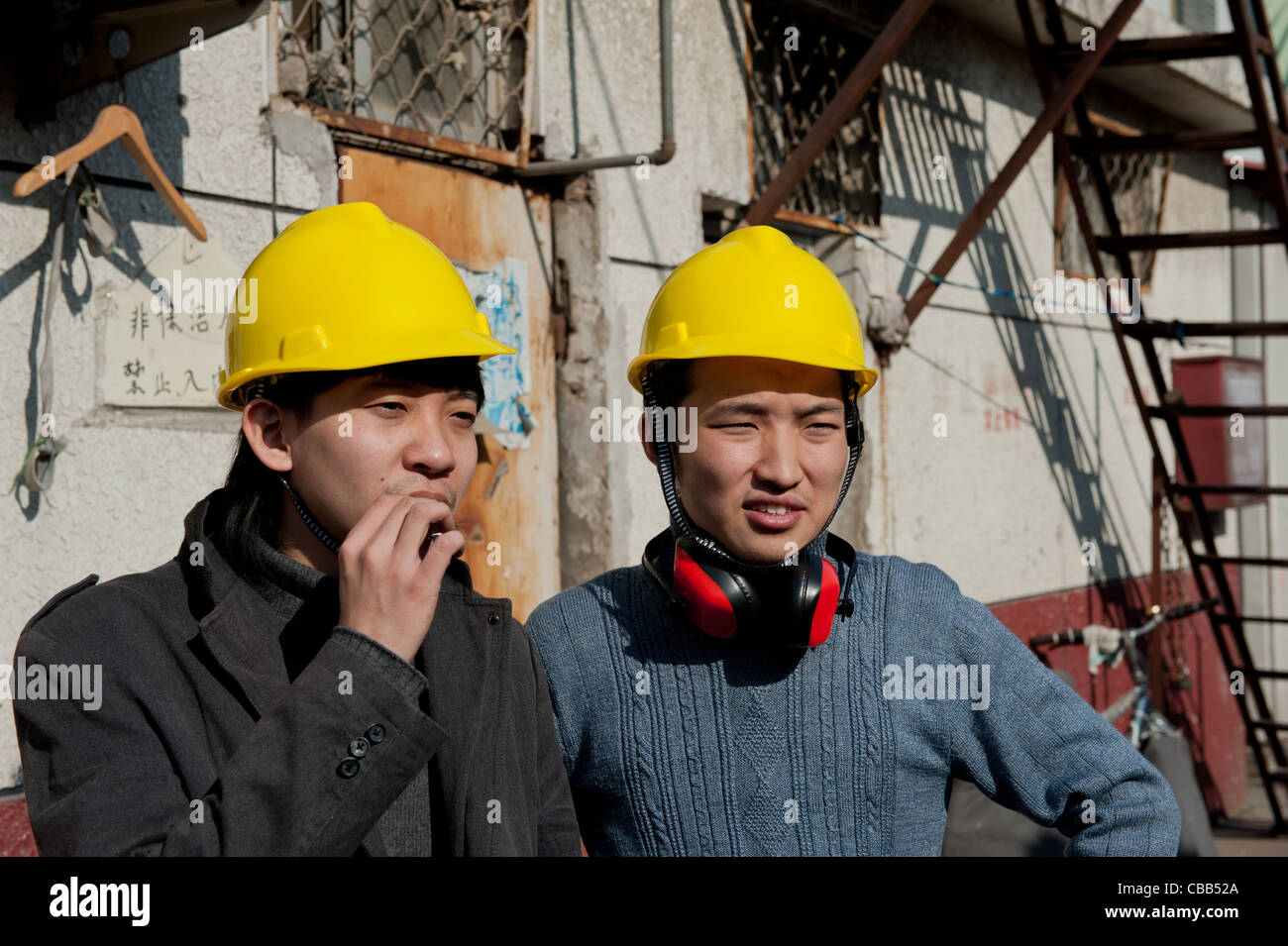Construction workers standing and smoking on a street in an industrial ...