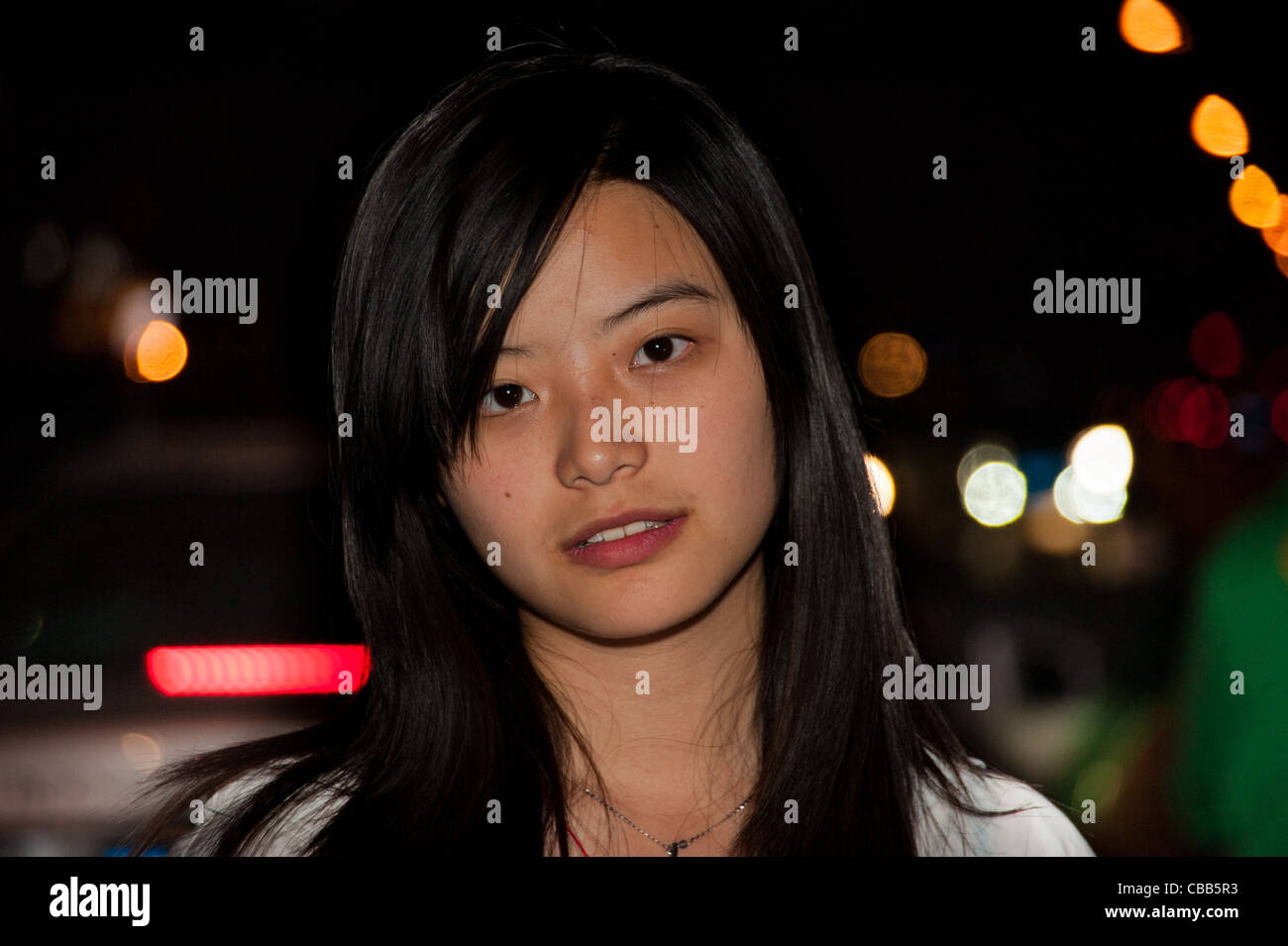 Young woman, at night on the streets of Beijing, looking into the ...