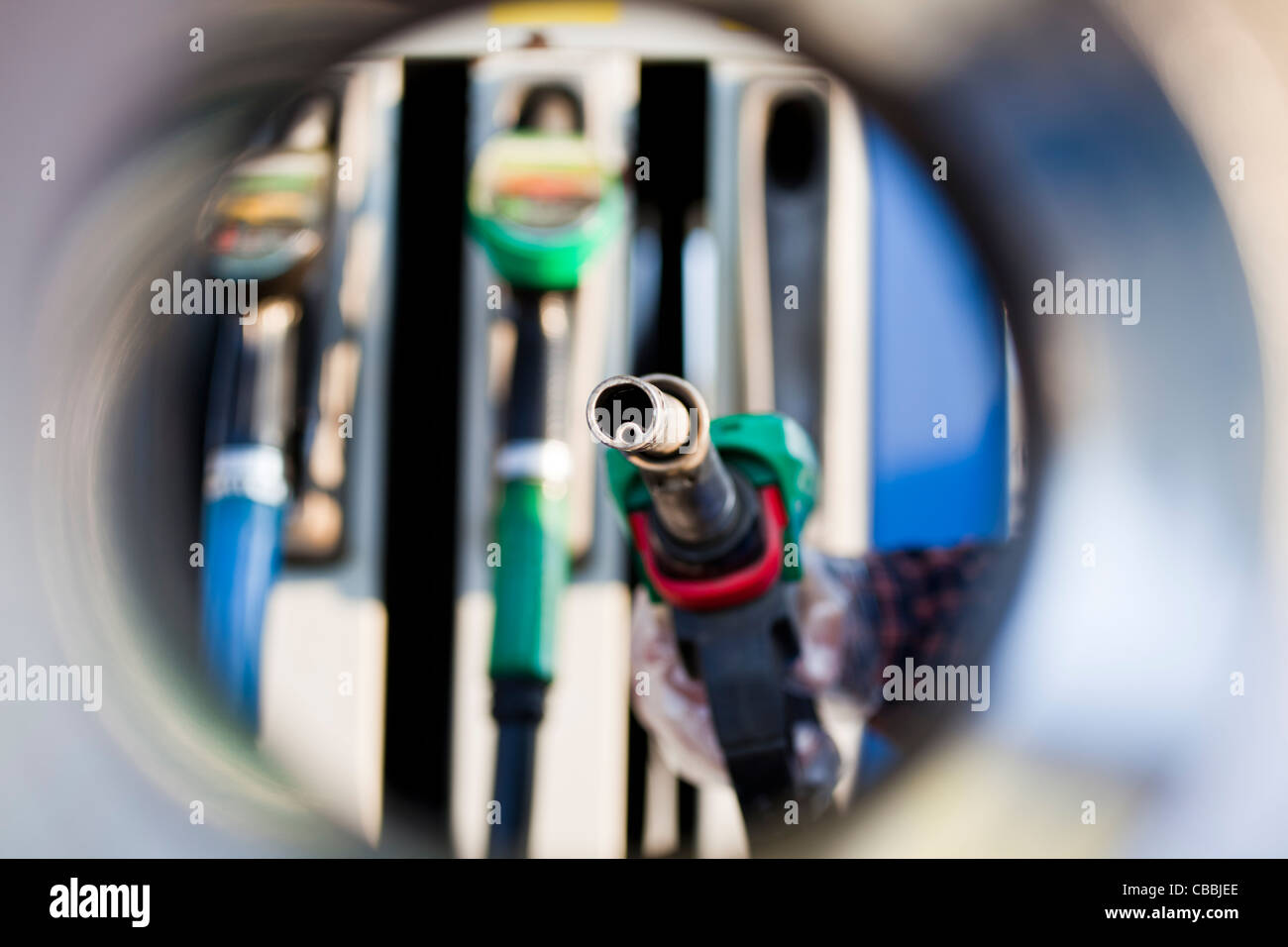 A view from car's tank to a fuel-pistol serving petrol at gas, petrol ...