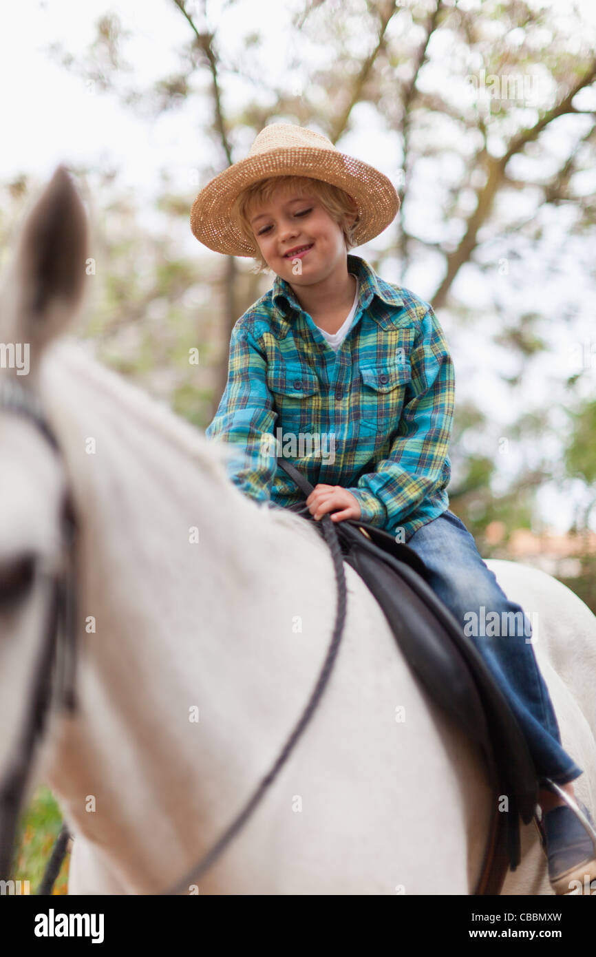 Smiling boy riding horse in park Stock Photo - Alamy