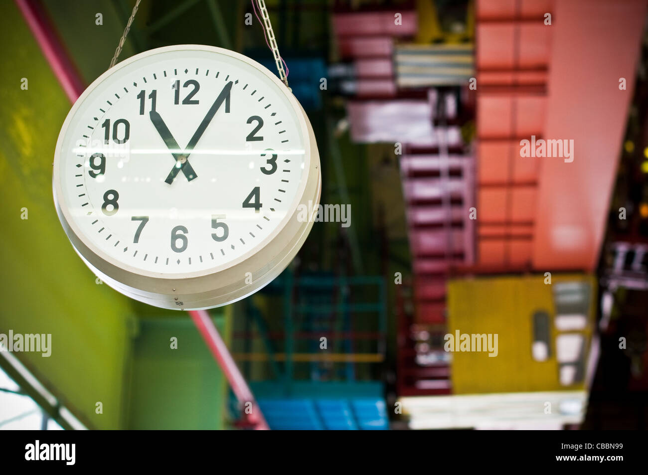 big clock hanging down from factory ceiling Stock Photo - Alamy