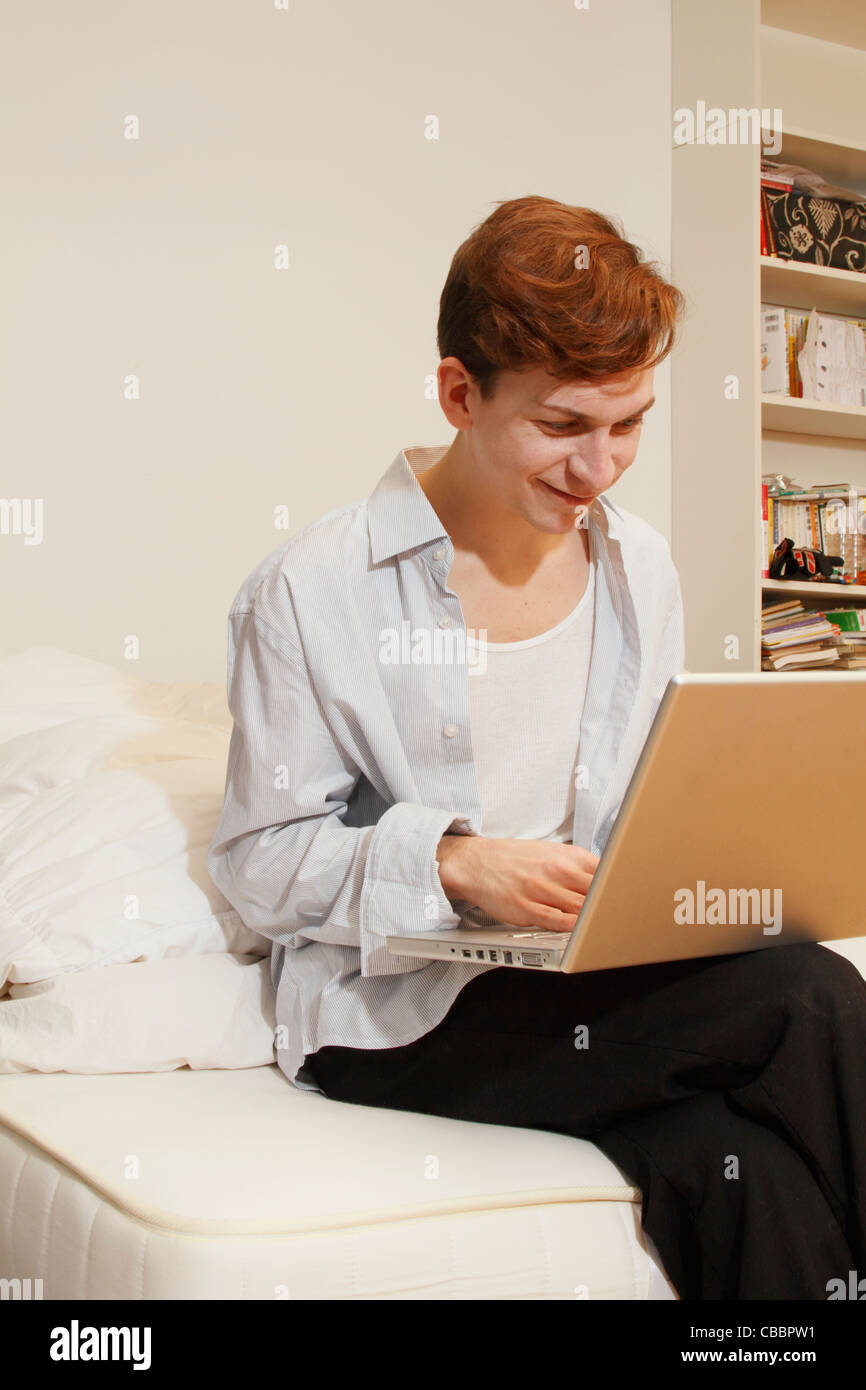Smiling man using laptop in living room Stock Photo - Alamy
