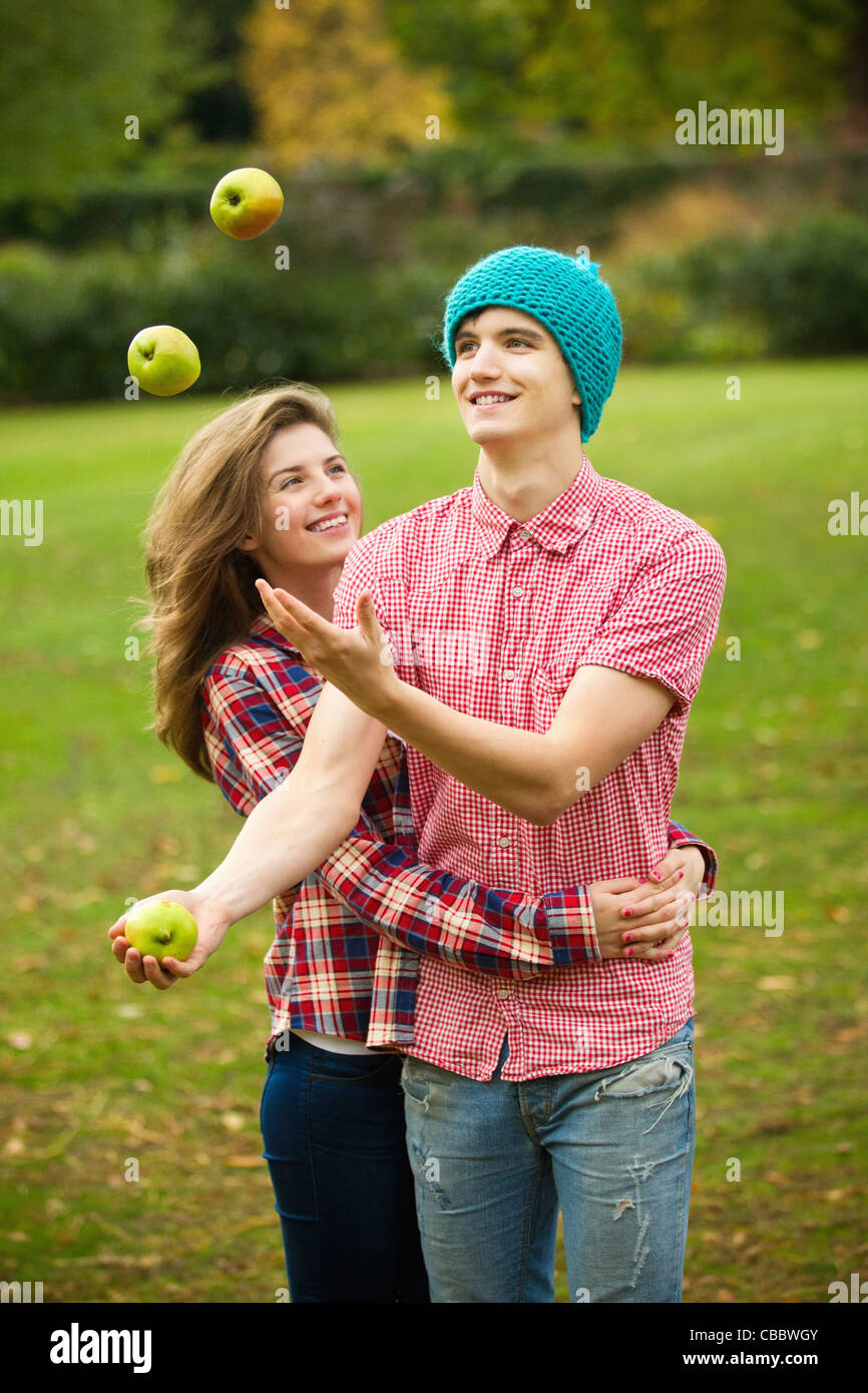 Teenage couple juggling apples in park Stock Photo - Alamy