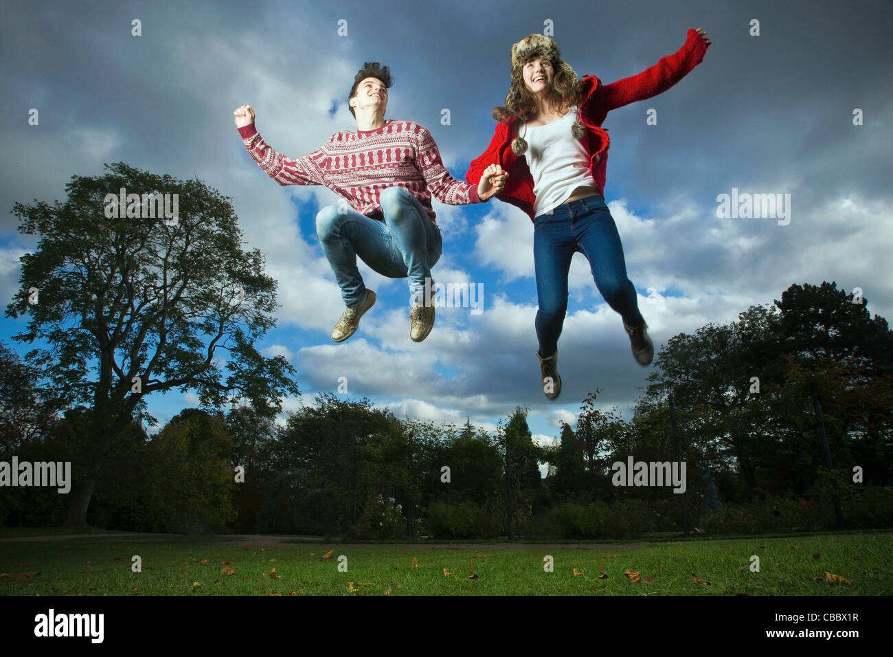 Teenage couple jumping for joy in park Stock Photo - Alamy