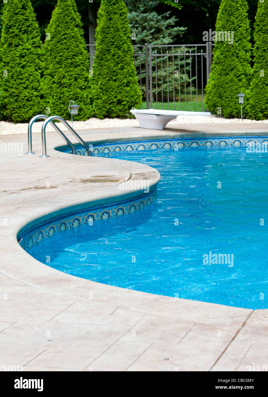 Generic small fenced swimming pool with diving board Stock Photo - Alamy